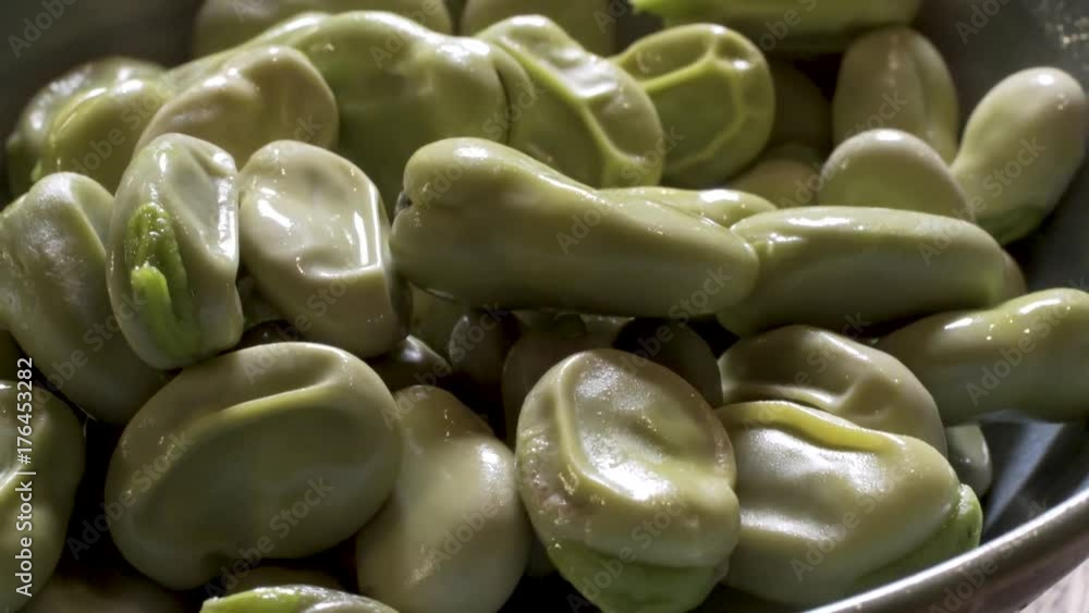 Close up of Fava beans spinning. The beans have been boiled so the skin ...
