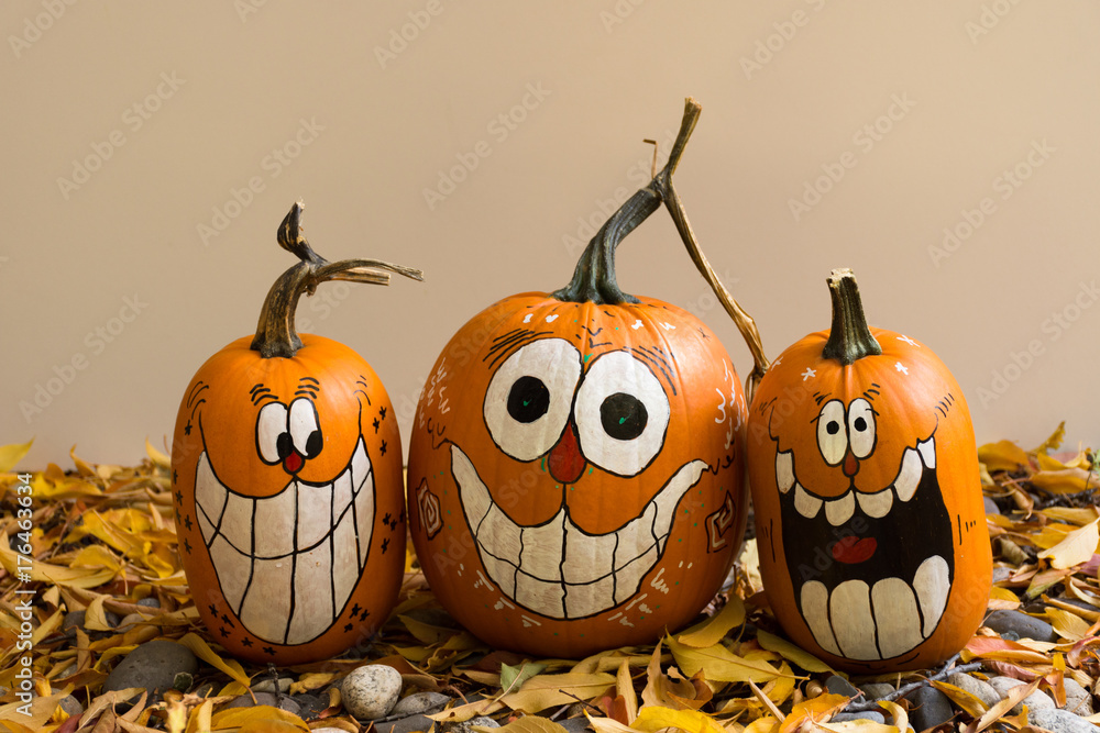 Three smiling and laughing pumpkins with painted faces that have oval ...