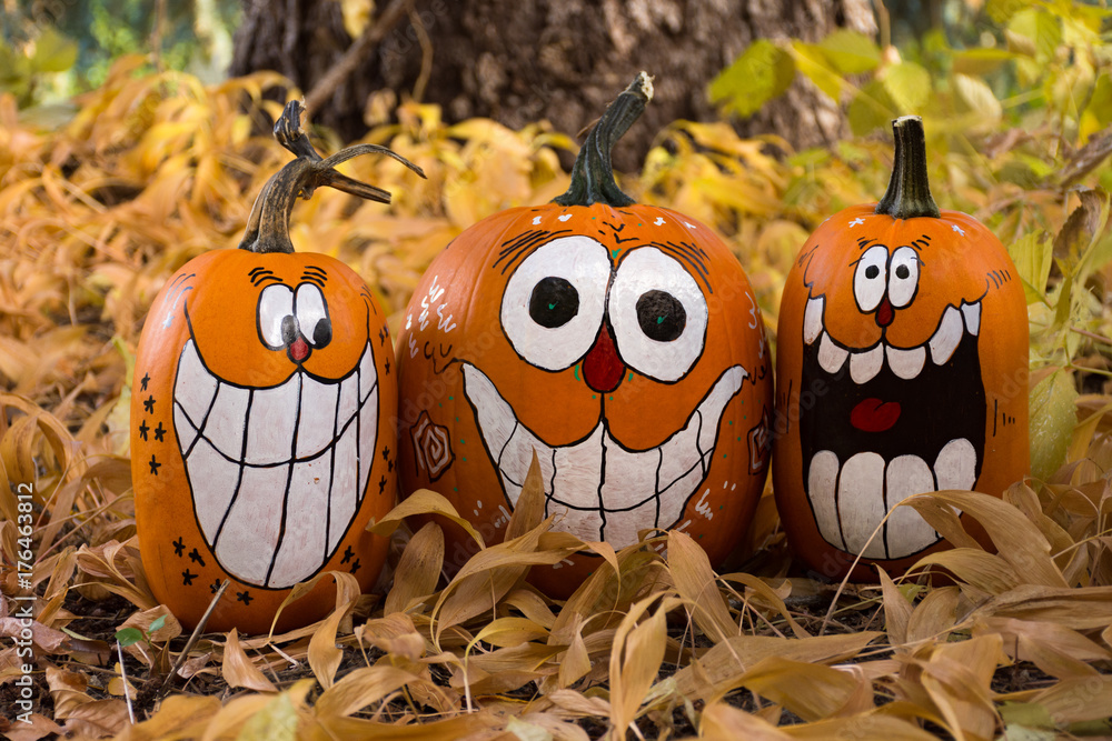 Three smiling and laughing pumpkins with painted faces that have oval ...