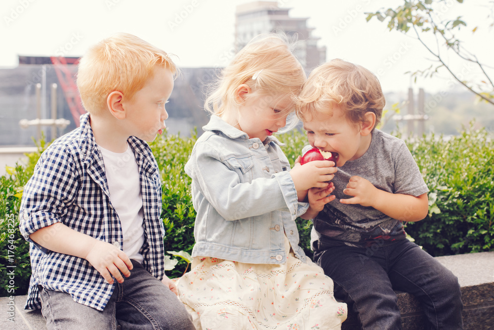 Group portrait of three white Caucasian cute adorable funny children toddlers sitting together ...