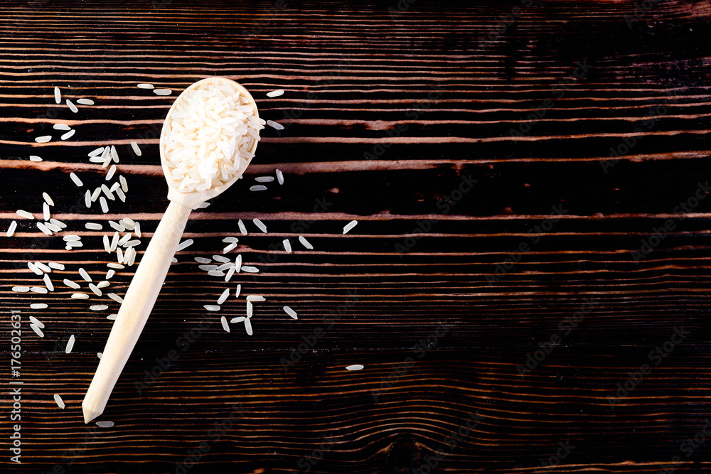 Raw and uncooked white rice in wooden spoon on wood background with ...