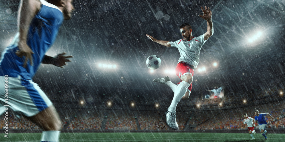 Soccer players performs an action play on a professional rainy stadium ...