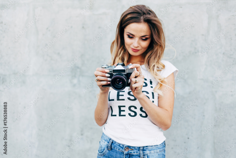 Stylish woman photographer in white T-shirt with word "less" with retro ...