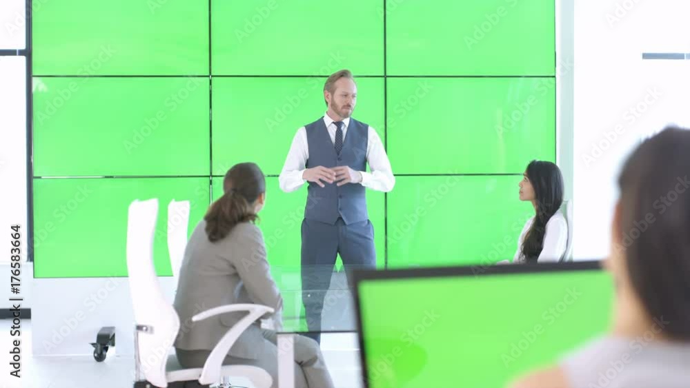 Corporate business team in a meeting with green screen video wall ...