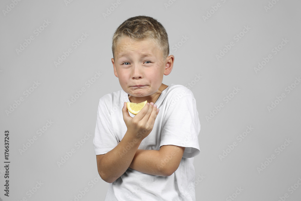 Little, blond boy biting into a lemon and make a face Stock Photo ...