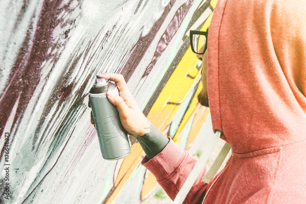 Street artist painting graffiti with color spray his art on the wall ...