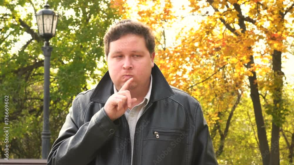 Handsome man making a shushing gesture raising his finger to his lips ...