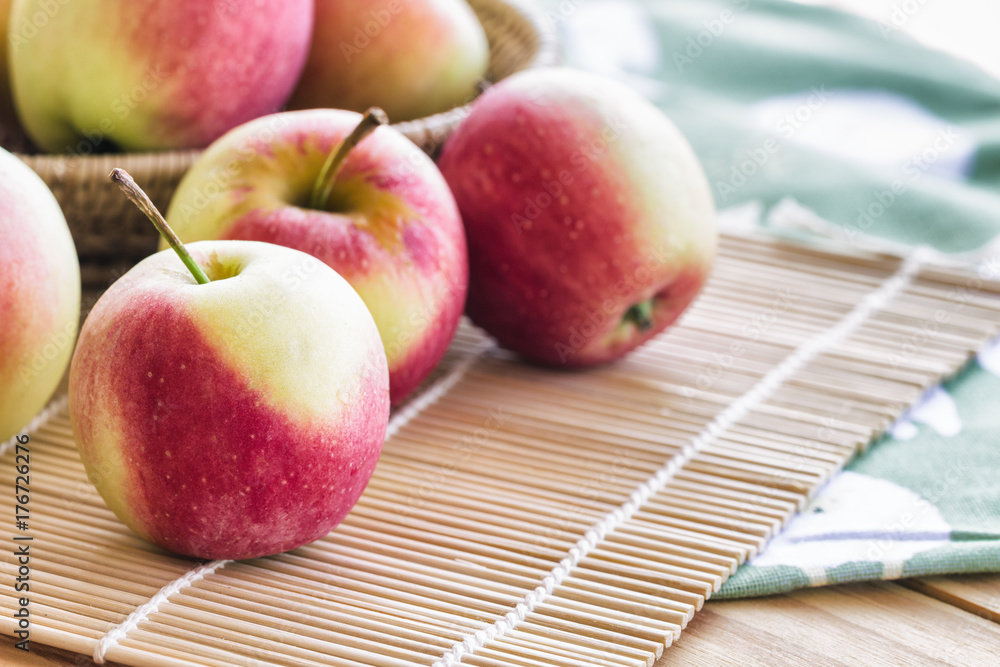 Stack of fuji apple on bamboo mat and in basket put on wood table for ...