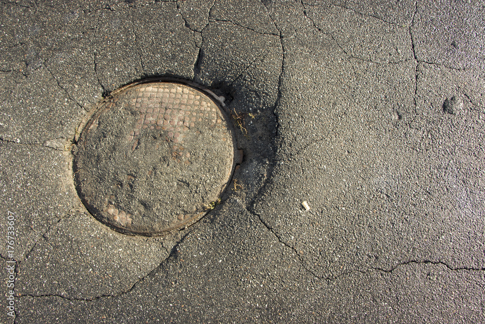 Large pothole in asphalt and circular manhole cover of sewage well in ...