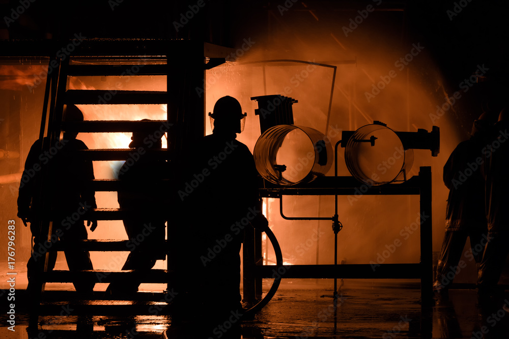 Firemen fighting a raging fire with huge flames of burning timber ...