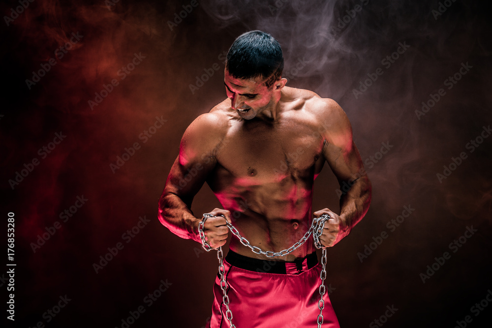 Portrait of muscular sportsman tearing metal chain.Black background ...
