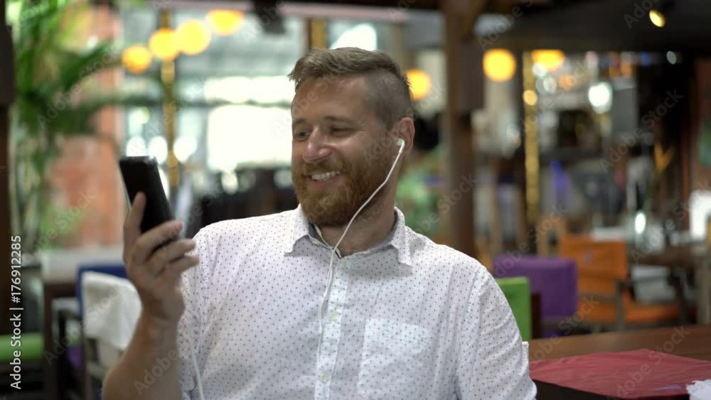 Handsome man having a videocall on smartphone in the restaurant ...