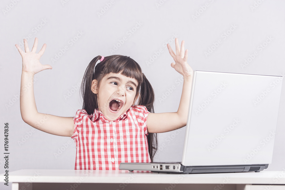 Angry little girl reacts while having problems using her computer foto ...