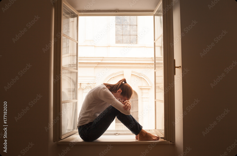 Sad lonely girl sitting next to window Stock Photo | Adobe Stock