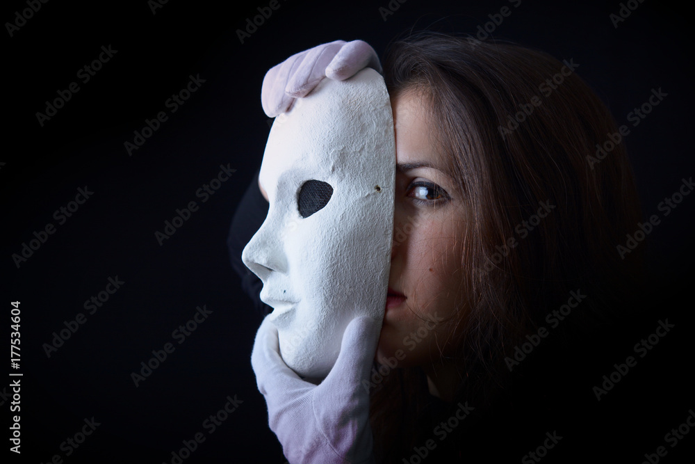 brunette girl is holding a theater mask in front of their face Stock ...