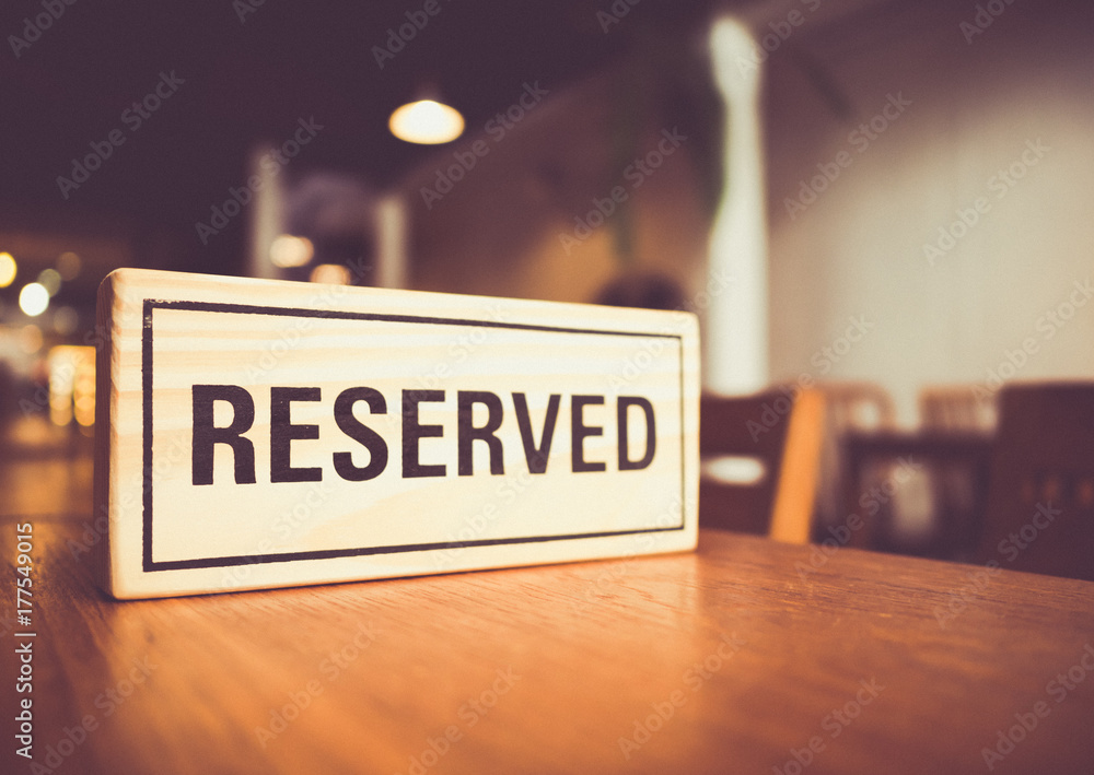 wooden reserved sign with capital letters on dining table in restaurant ...