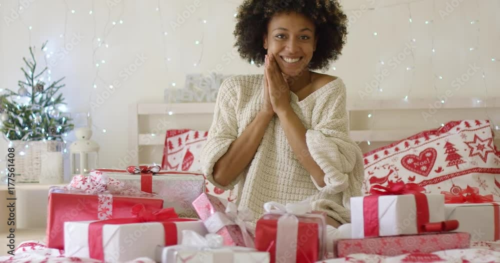 Excited young woman with a pile of Christmas gifts clapping her hands ...
