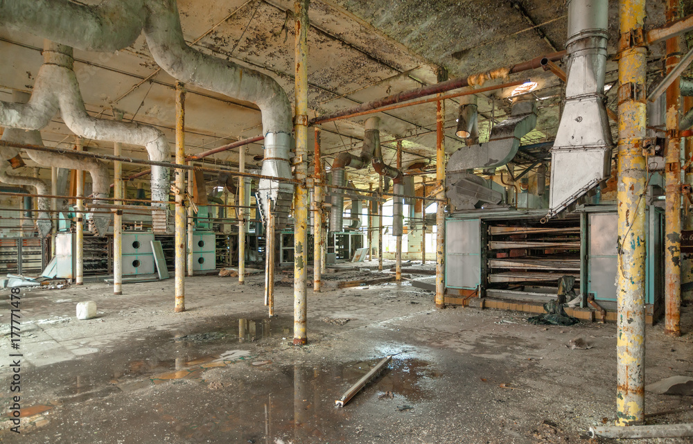 Destroyed production room of an old abandoned textile factory with remains of broken equipment ...