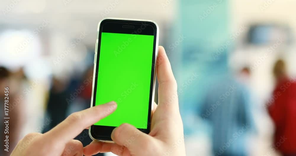 Man hand holding using green screen smart phone chromakey blank display public space people app ...
