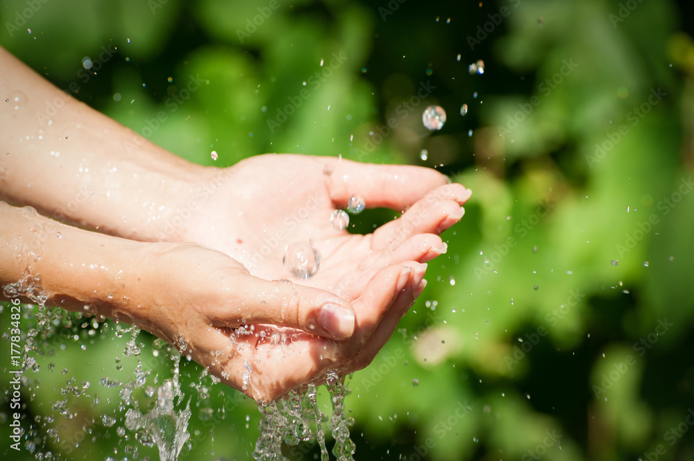 the side view of woman washing hand outdoors. Natural drinking water in ...