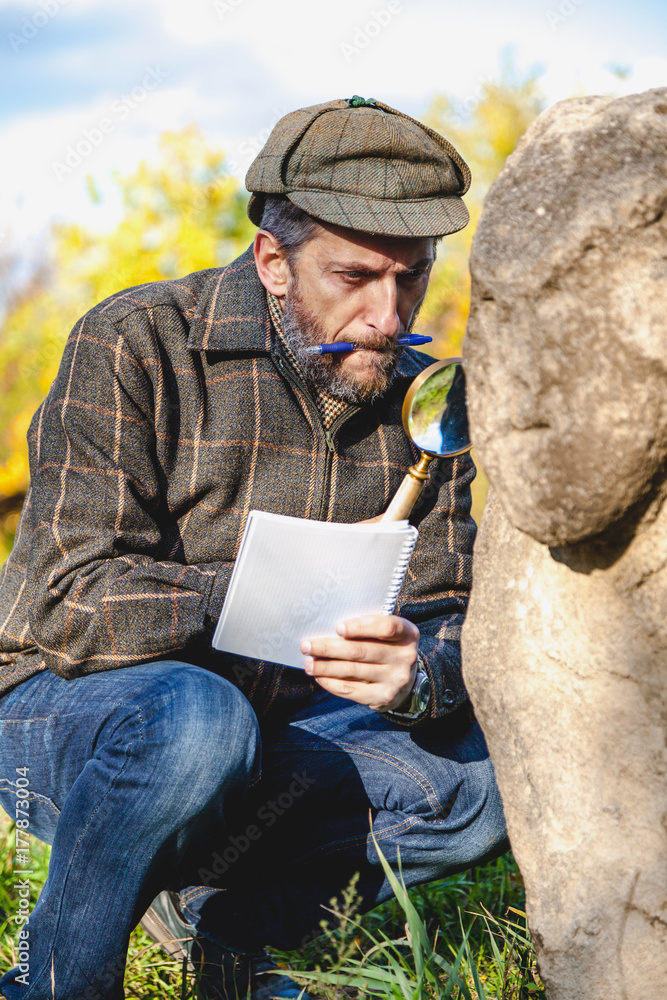 Foto de Scientific historian examines through magnifying glass stone ...