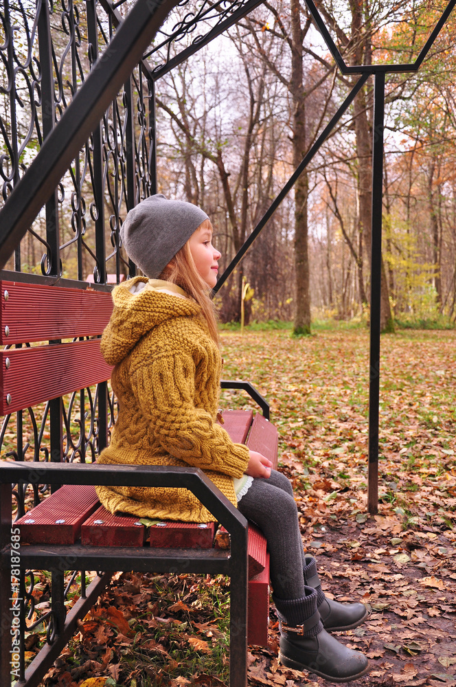 Little cute girl sitting on the bench Stock Photo | Adobe Stock