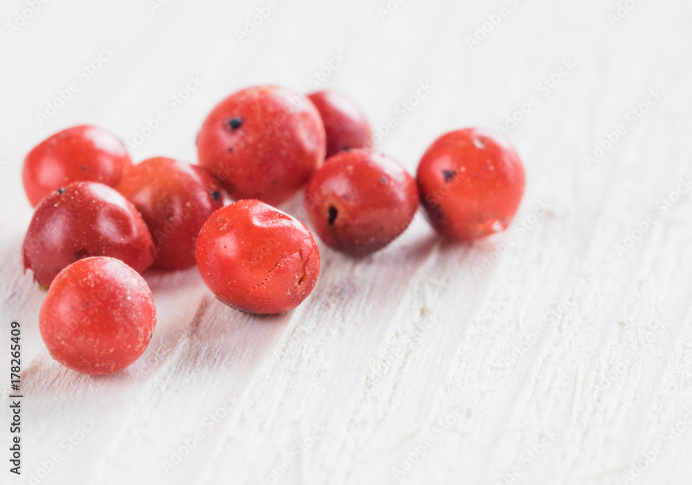 Heap of dried pink pepper berries on white wooden table. Close up view ...