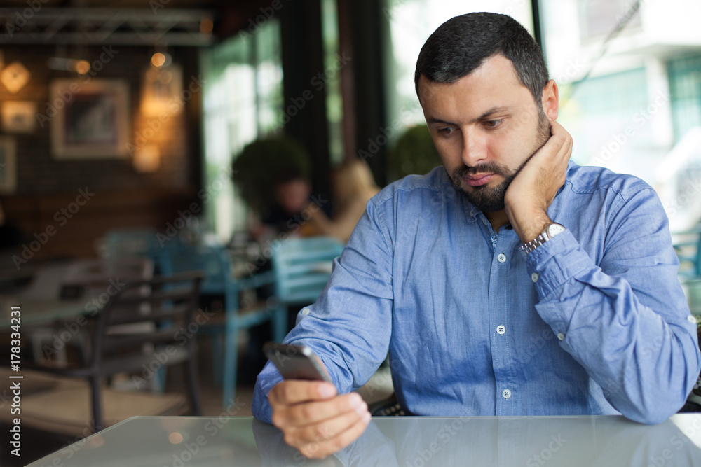Worried man looking at phone Stock Photo | Adobe Stock