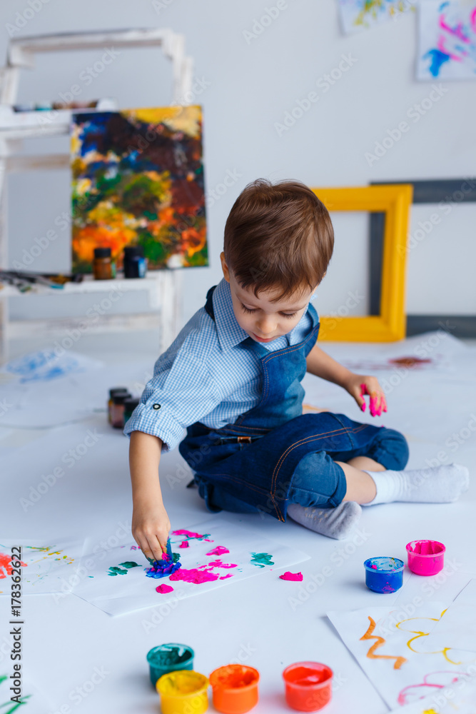 Cute, happy, white boy in blue shirt and jeans drawing with bright ...