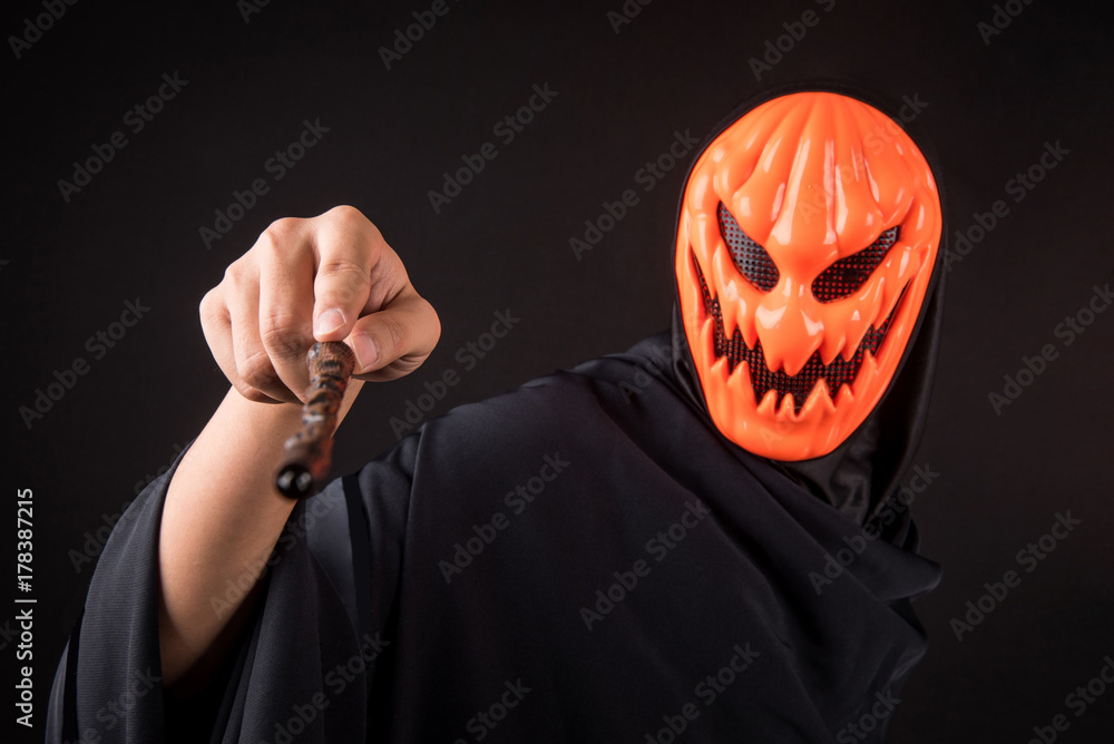 Mystery man with orange pumpkin evil mask holding magic wand on black ...