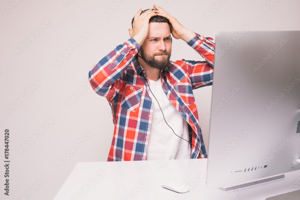 Sad young man with headset confused and unfappy look at monitor screen ...