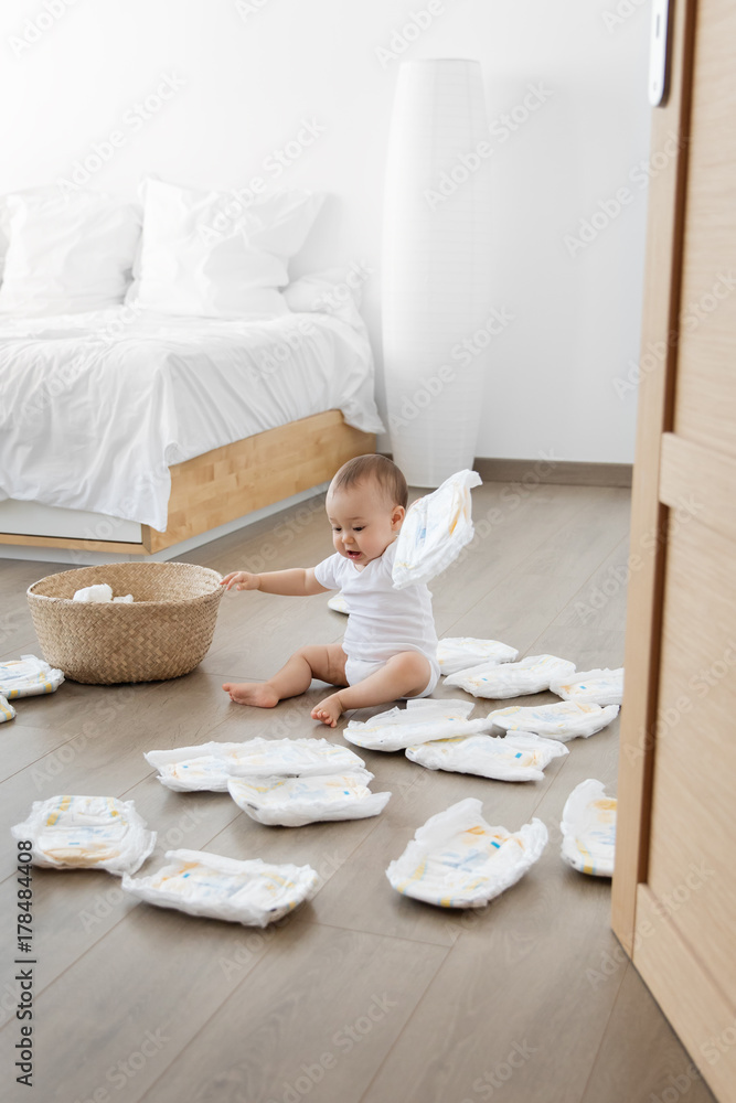 Baby sitting on bedroom floor making a mess with diapers Stock Photo ...