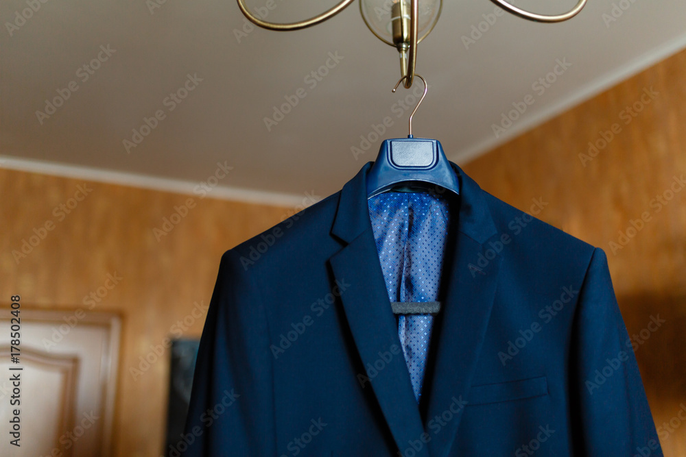 Dark blue suit hanging on a hanger in the office. Dress is formal in ...