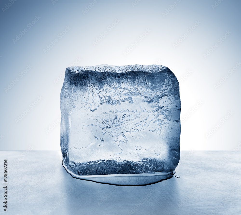Frosty translucent, frigid cold blue ice block melting to create pool ...