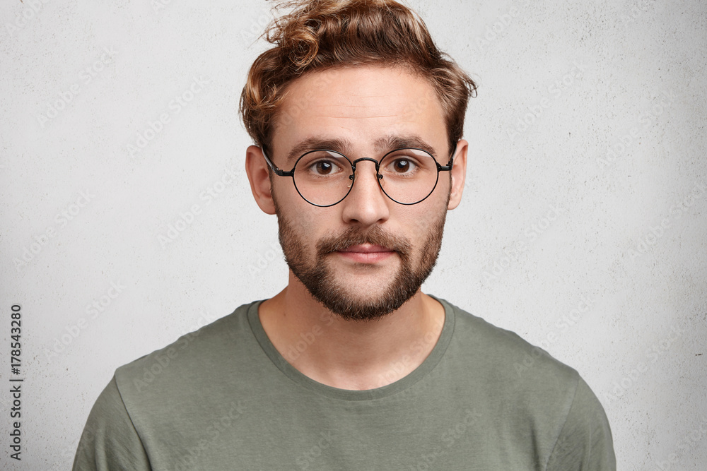 Attractive man with dark eyes, beard and trendy hairdo wears casual ...