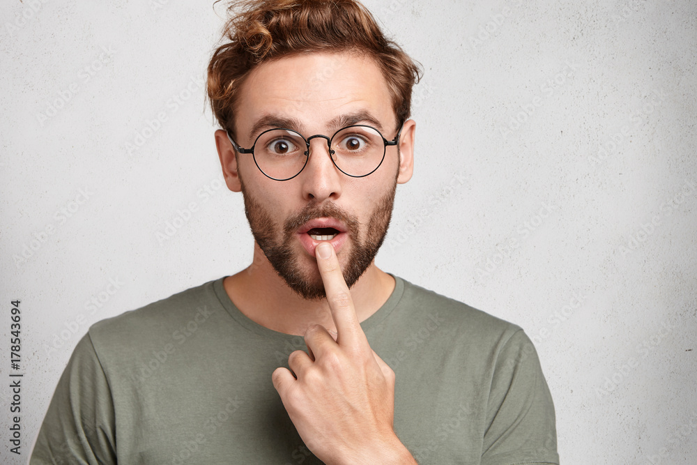 Funny male philosopher in round spectacles stares at camera, keeps ...