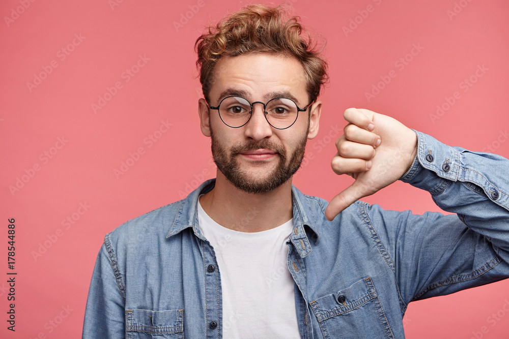 Stylish fashionable male poses indoors against pink background, assess ...