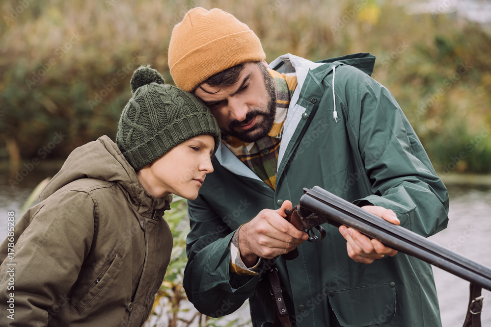 Father showing son how to load gun Stock Photo | Adobe Stock