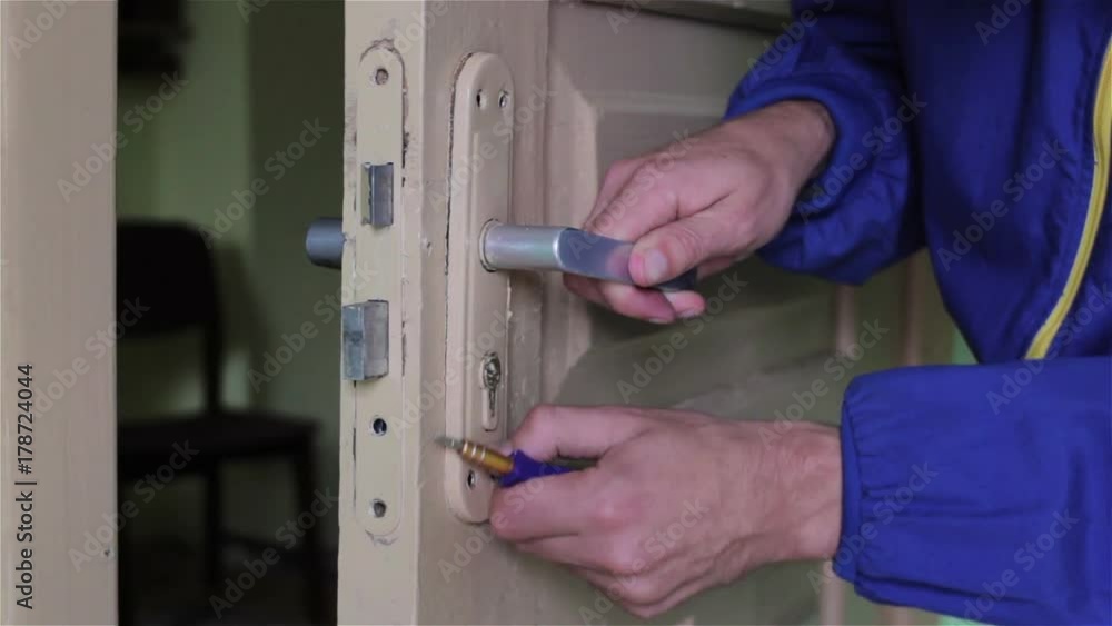 Worker Setting The Door Lock/The man repairs the door lock in the room ...