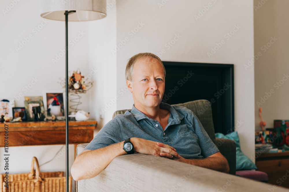 Interior portrait of handsome man resting at home, sitting on the couch ...