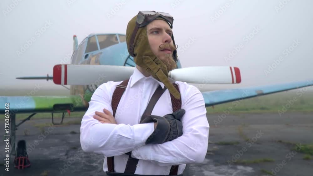 A strong pilot in a 60th suit stands in a brave pose in front of a ...