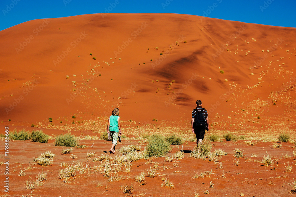 Boy and girl walking barefooted on hot red desert sand in Sossusvlei ...