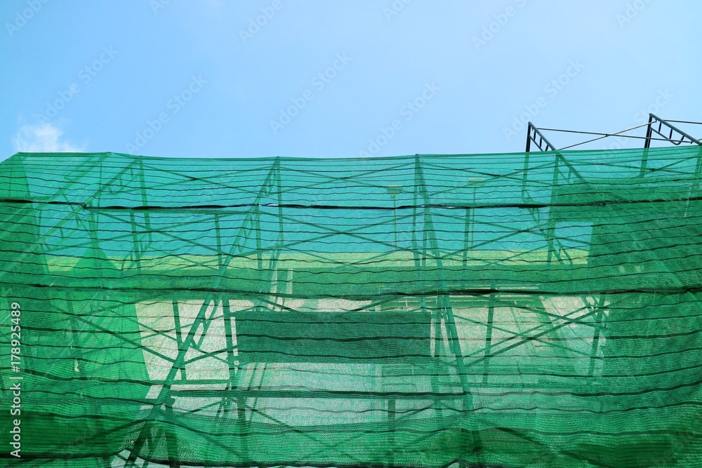 Construction scaffolding with green cover at the building. Copy space ...