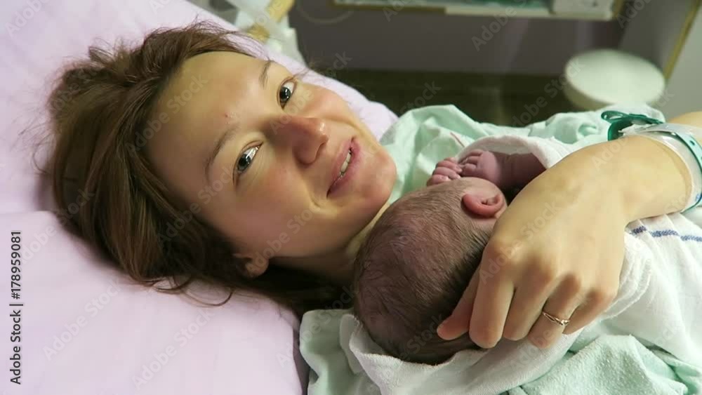 Childbirth. Mother holding her newborn baby child after labor in a ...