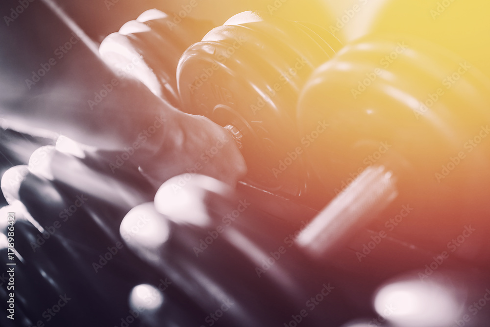 Dumbbell. Close-up man grabs a heavy dumbbell in the gym with his hand ...