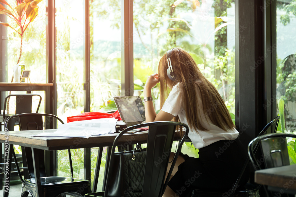 Asian students in uniform with headphone studying in coffee shop using ...