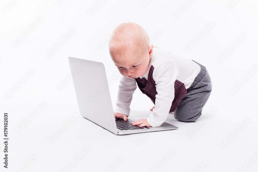cute little baby boy sitting on a white background in front of a laptop ...