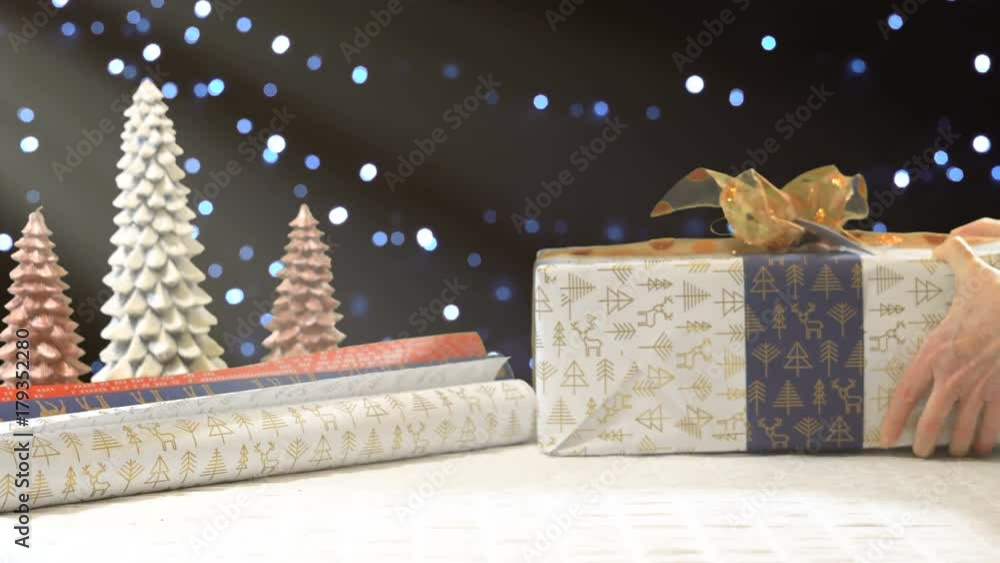 Stacking modern wrapped Christmas gifts on table against bokeh fairy ...