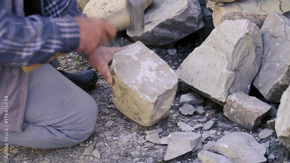 Stonemason cutting a block of granite with sledgehammer. Pitching ...