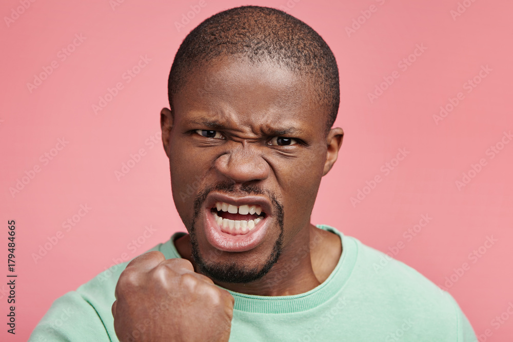 Outraged furious dark skinned man threatens with fist, has quarrel ...
